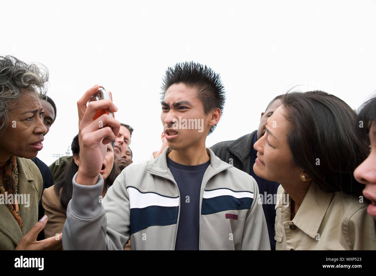 Angry young man holding mobile phone in crowd Stock Photo - Alamy