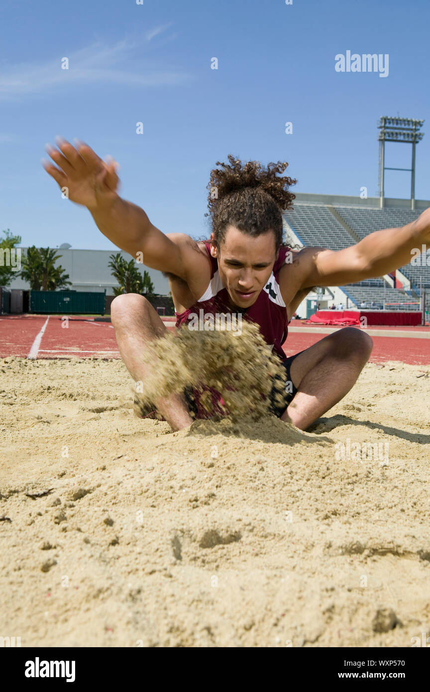 Male long jumper landing in sand pit Stock Photo - Alamy
