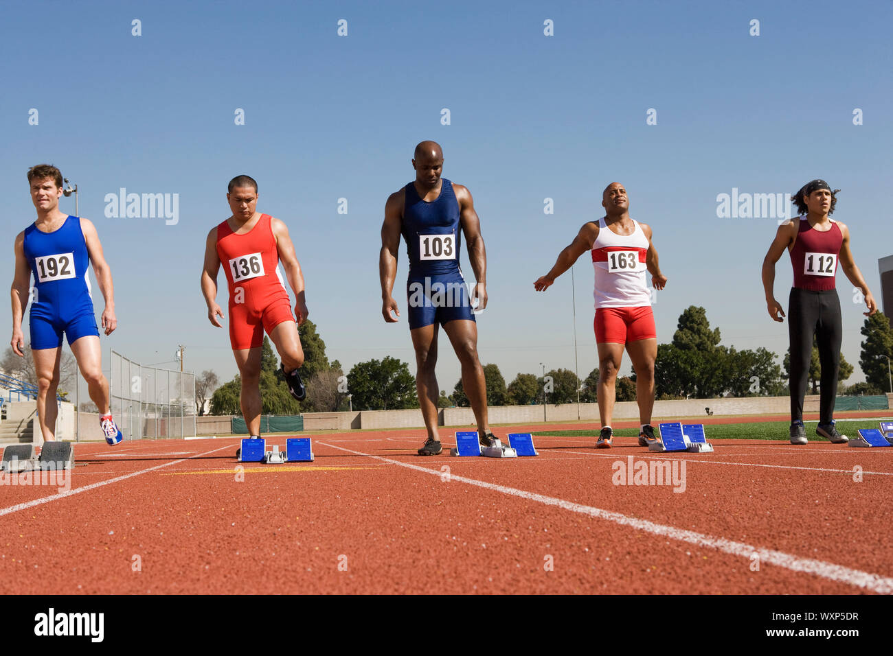 Athletes standing next to starting blocks, ready to run Stock Photo - Alamy