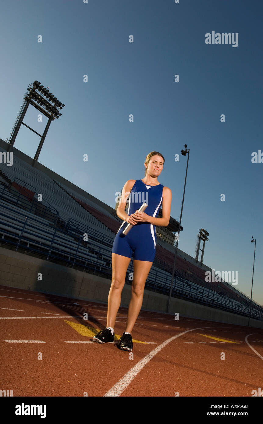 Female track standing on track holding relay baton Stock Photo - Alamy