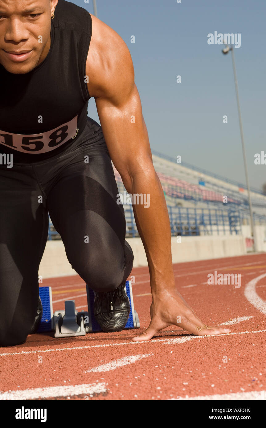Male track athlete on starting block Stock Photo - Alamy