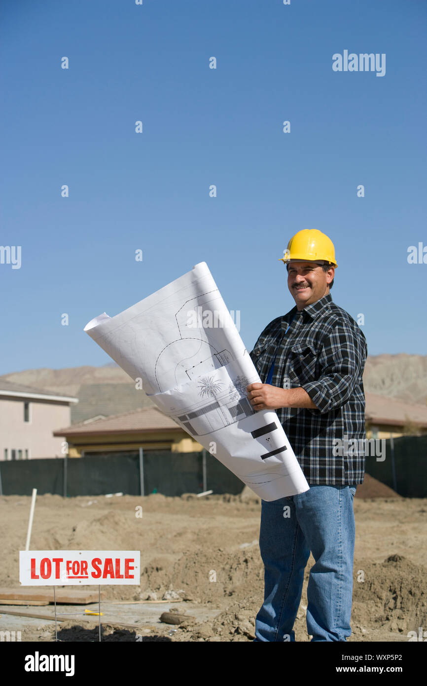 Construction worker holding building plans Stock Photo - Alamy