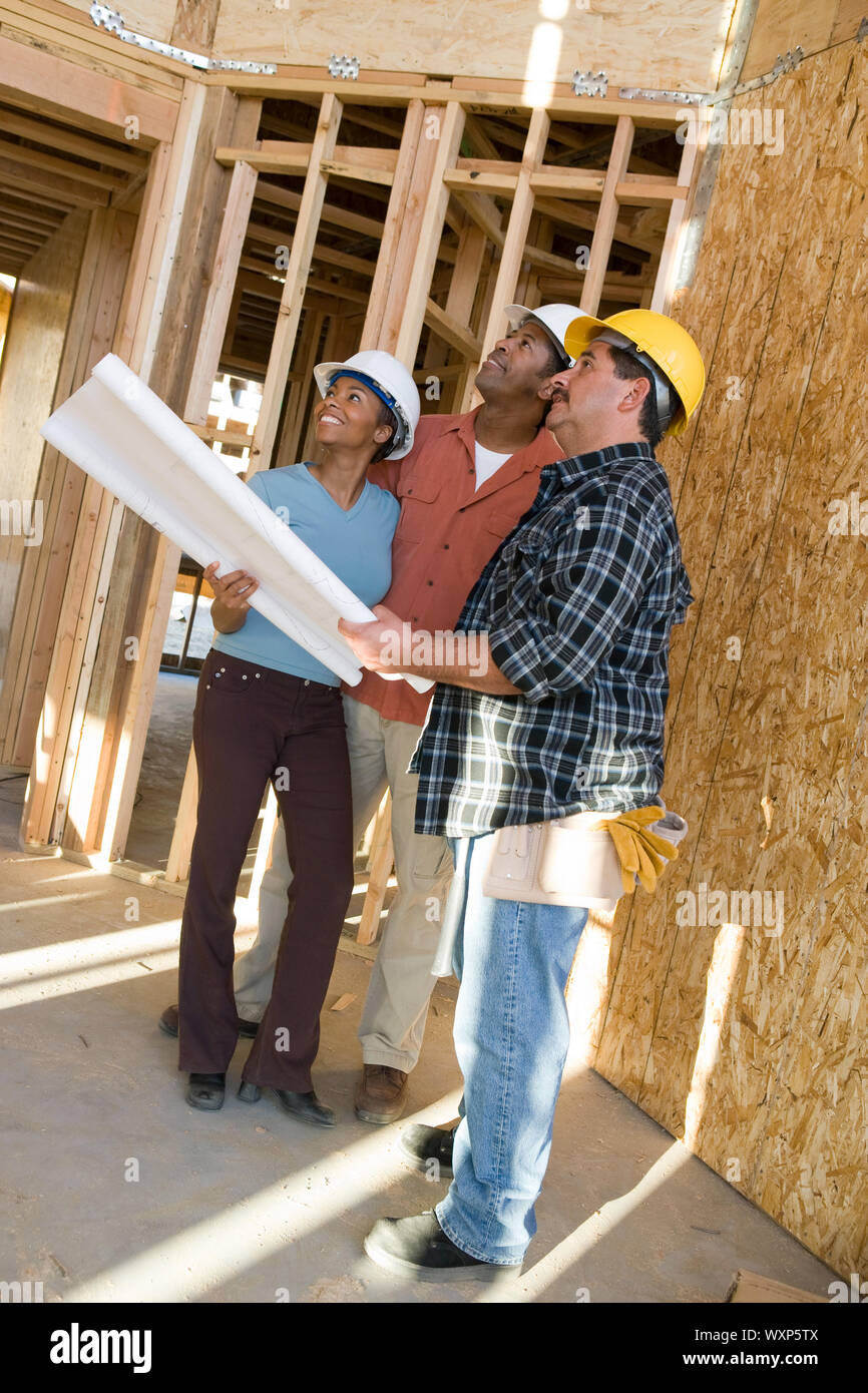 Young couple with construction worker in construction site Stock Photo ...