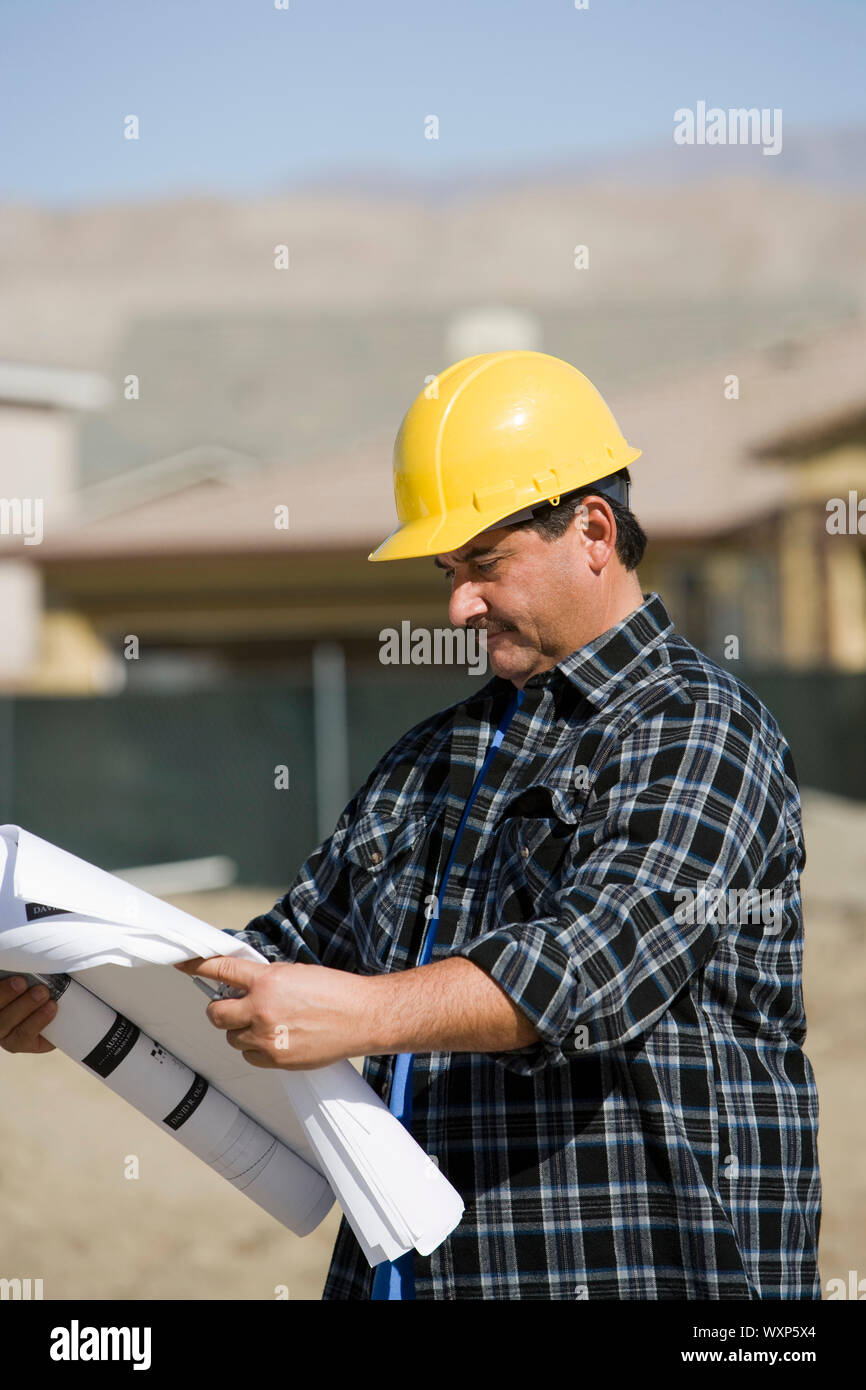 Construction worker examining blueprint Stock Photo - Alamy