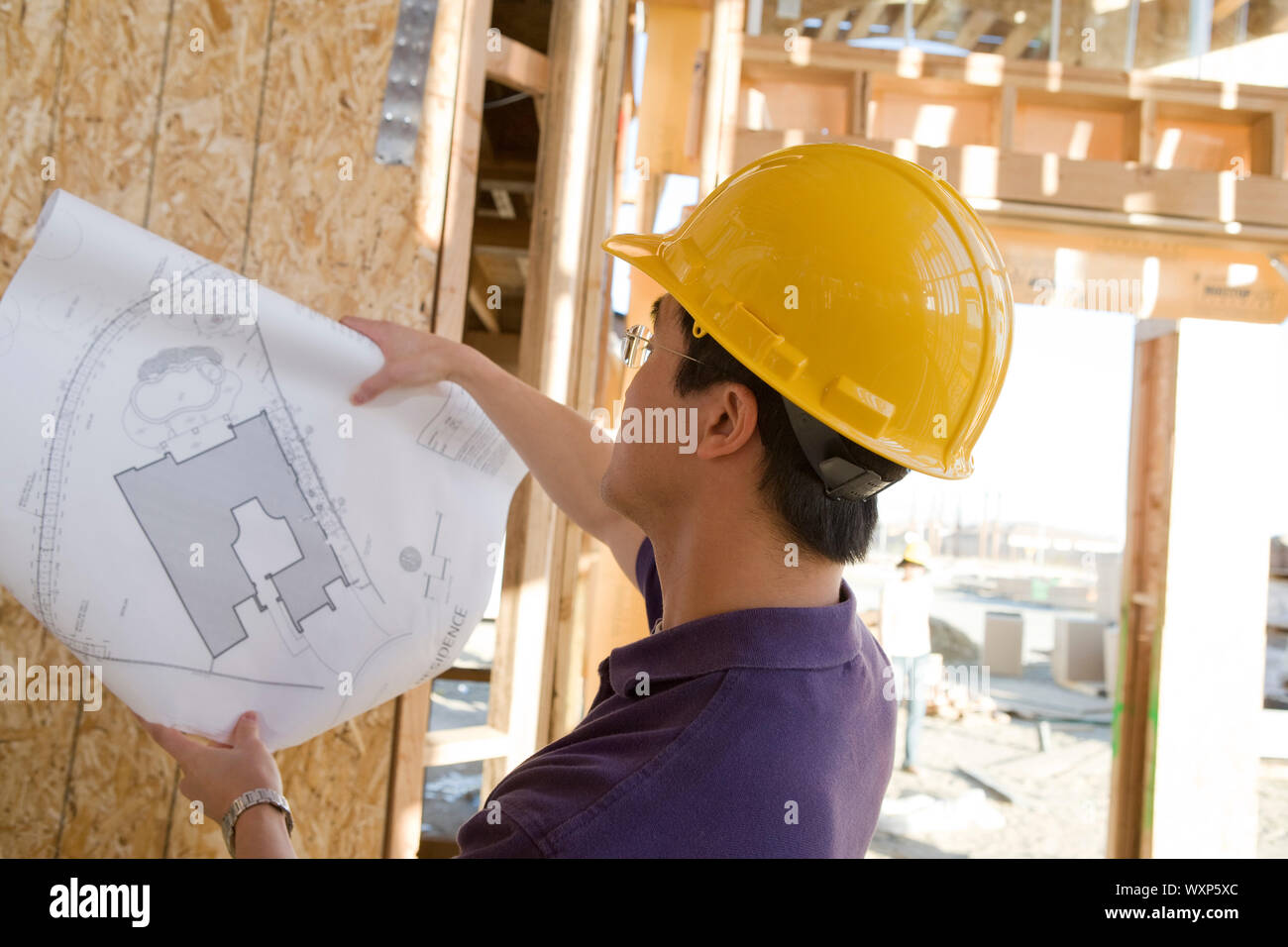 Worker holding blueprint in construction site Stock Photo - Alamy