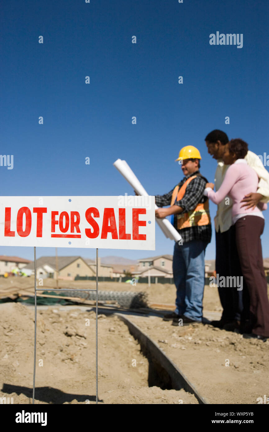 Couple with construction worker in construction site Stock Photo - Alamy
