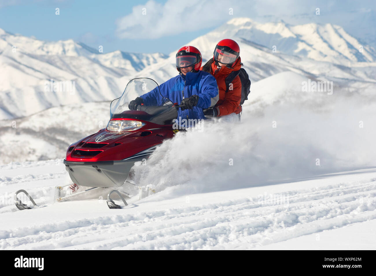 Couple Snowmobiling with Mountains in Background Stock Photo - Alamy