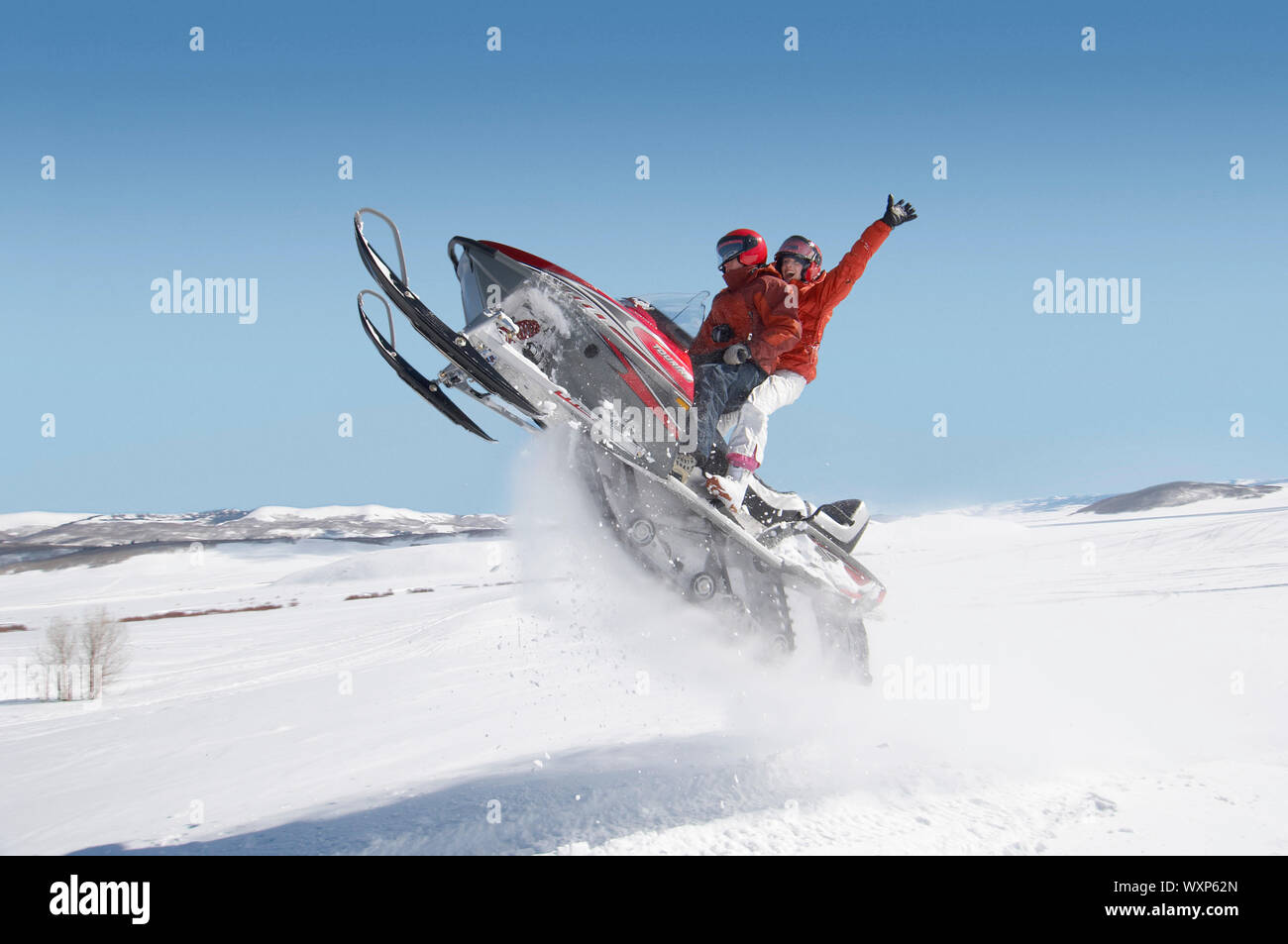 Couple Mid-air on Snowmobile Stock Photo - Alamy