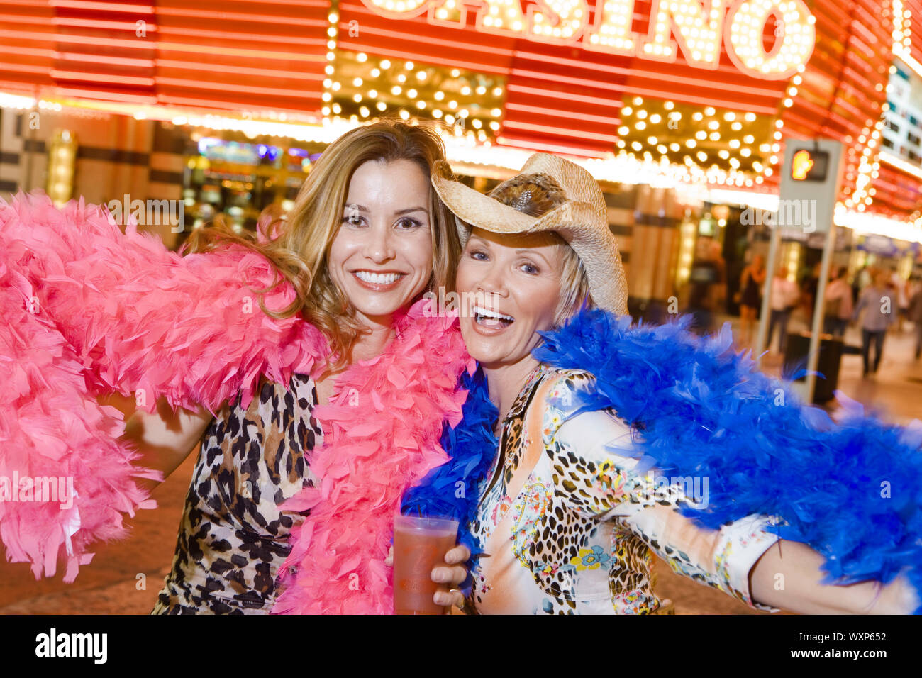 Two women wearing feather boas in front of casino building, portrait ...