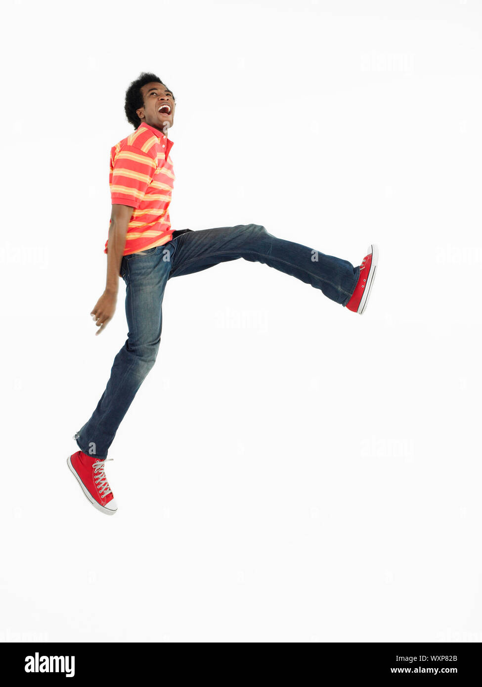 Full length side view of an afro man jumping against white background ...