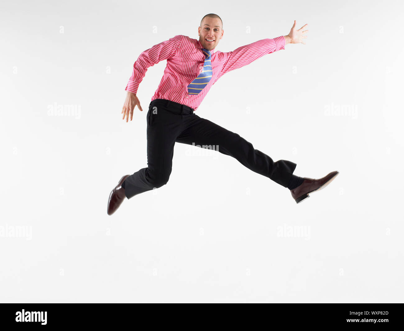 Full length portrait of a bald businessman jumping against white ...