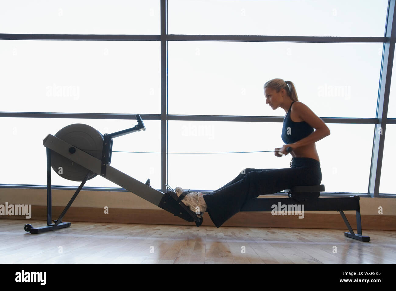 Side view of fit young women using rowing machine in health club Stock ...