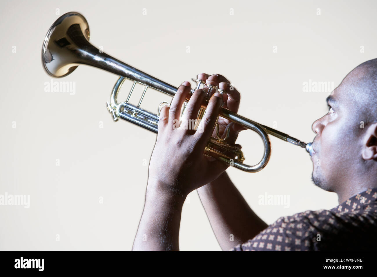 Side view of an African American man playing trumpet against gray ...