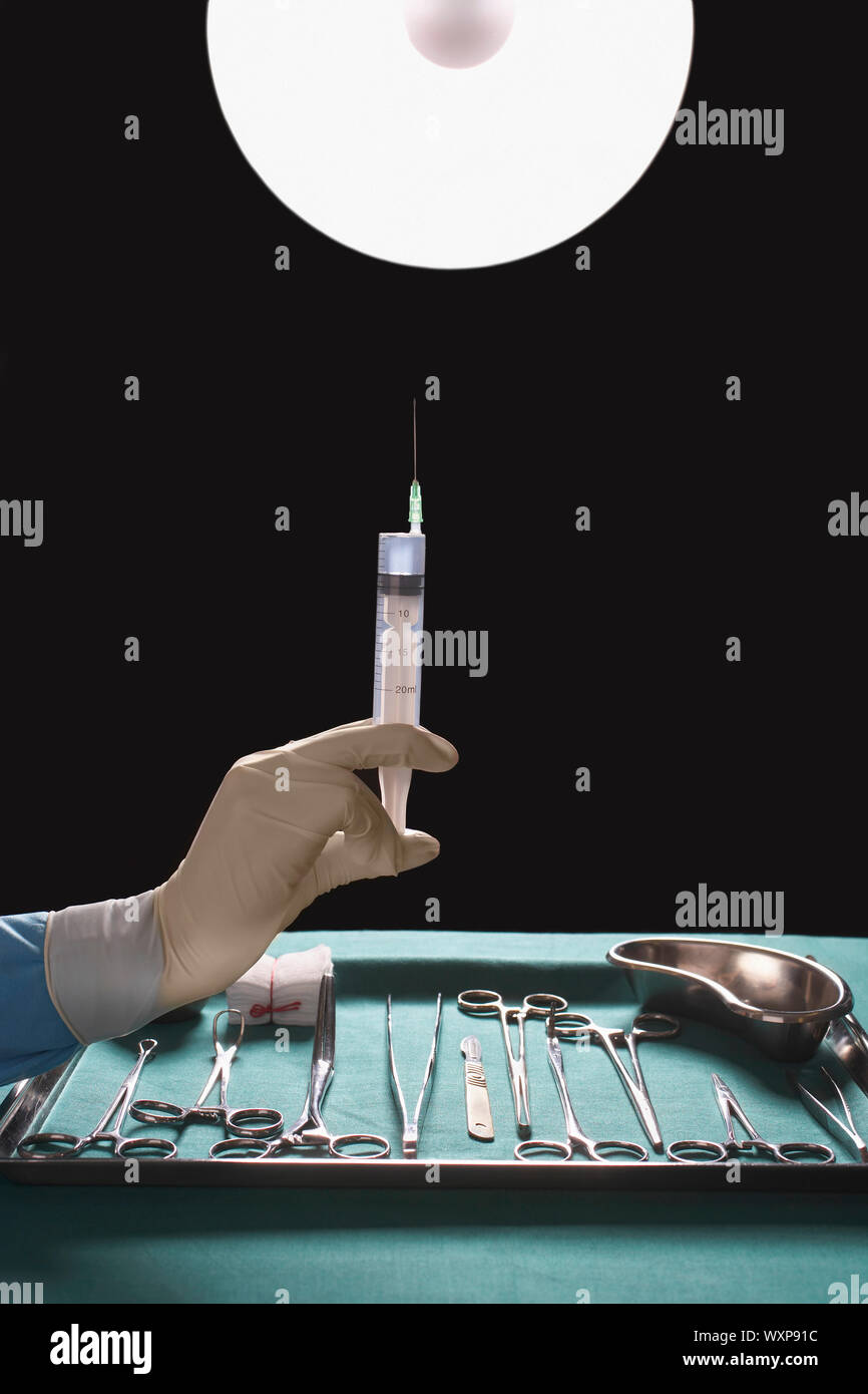 Closeup of a surgeon's hand holding syringe by medical equipment in ...