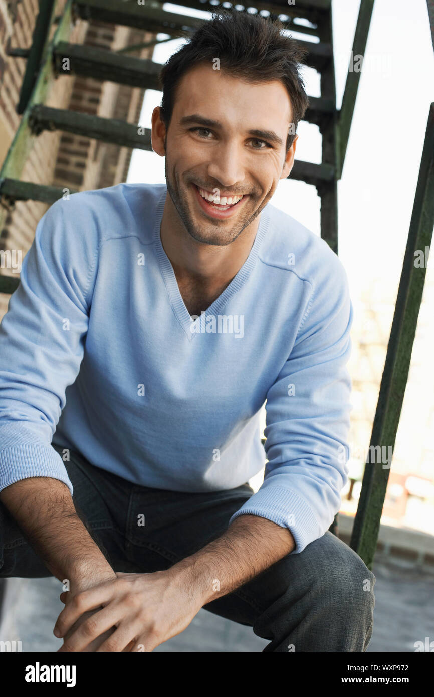 Young Man Sitting on Fire Escape Stock Photo - Alamy
