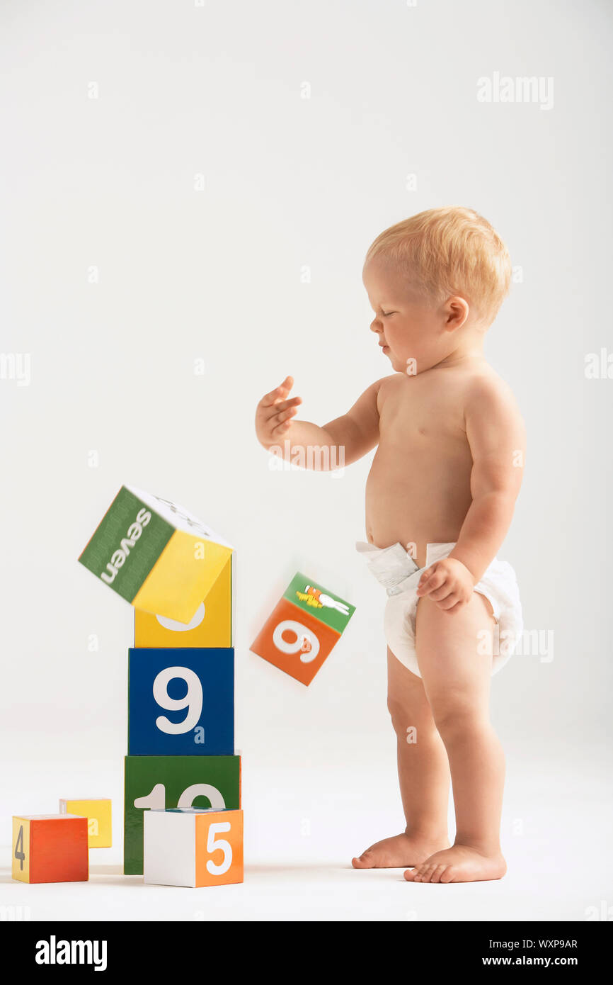 Side view of baby knocking building blocks isolated on white background ...