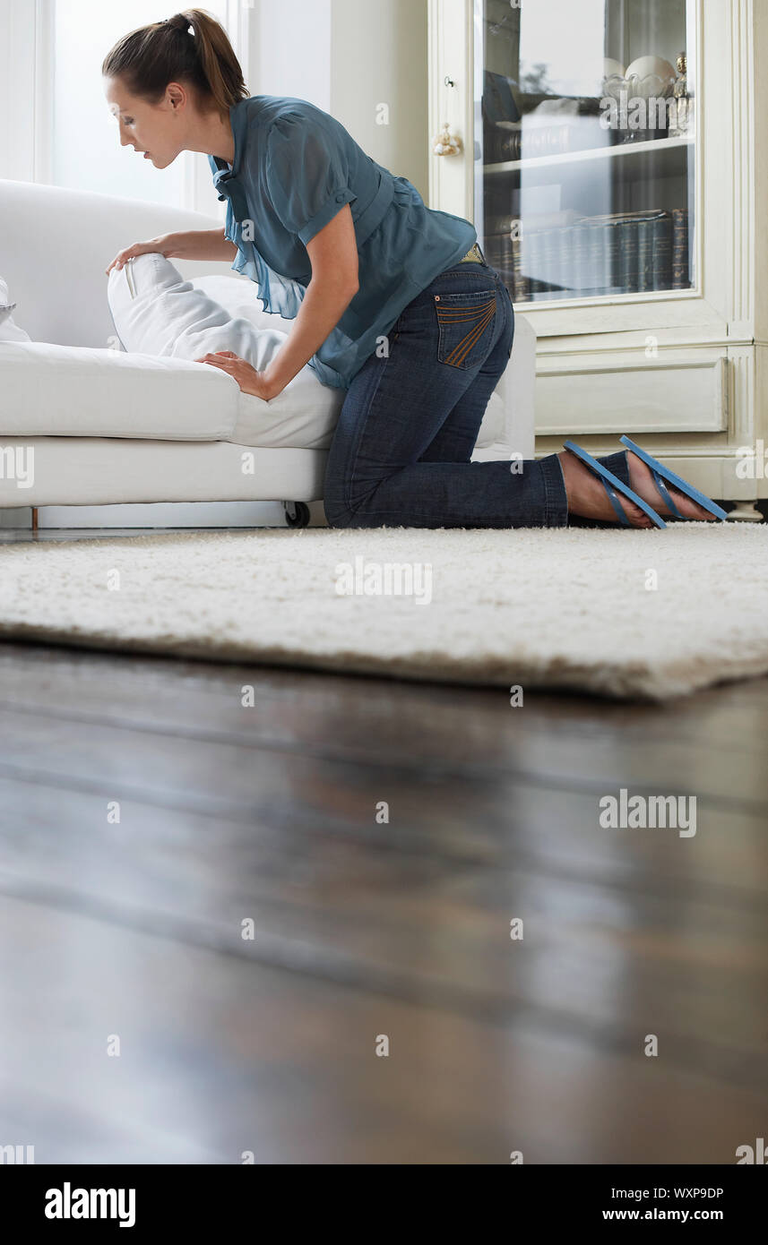 Middle aged woman finding something on sofa Stock Photo - Alamy