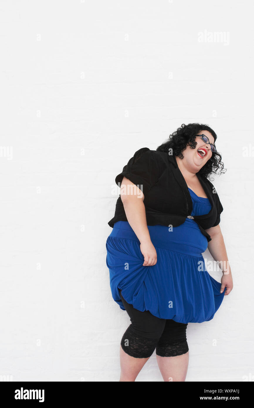 Overweight woman laughing while curtseying against white background ...