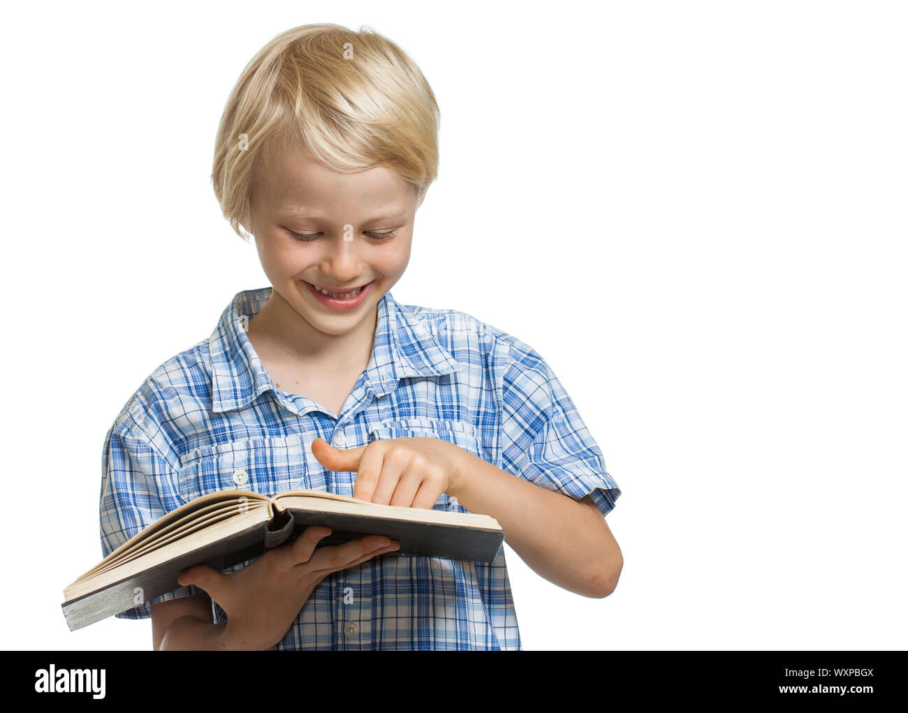 A smiling young boy holding and reading a thick book. Isolated on white ...