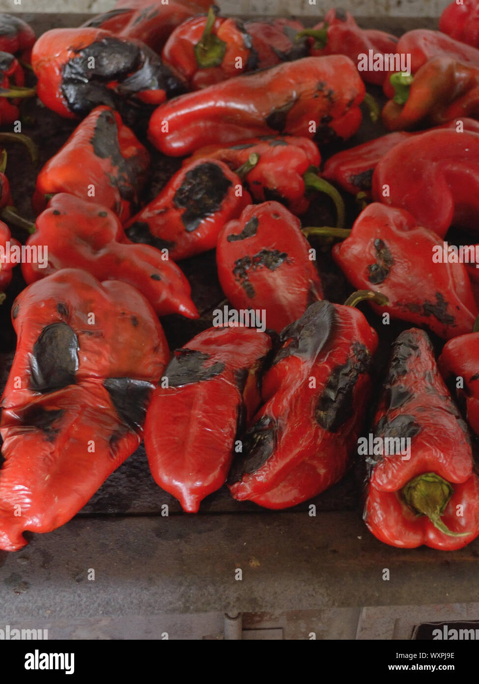 Roasted red bell peppers on old black wood cook stove. Baked sweet red ...