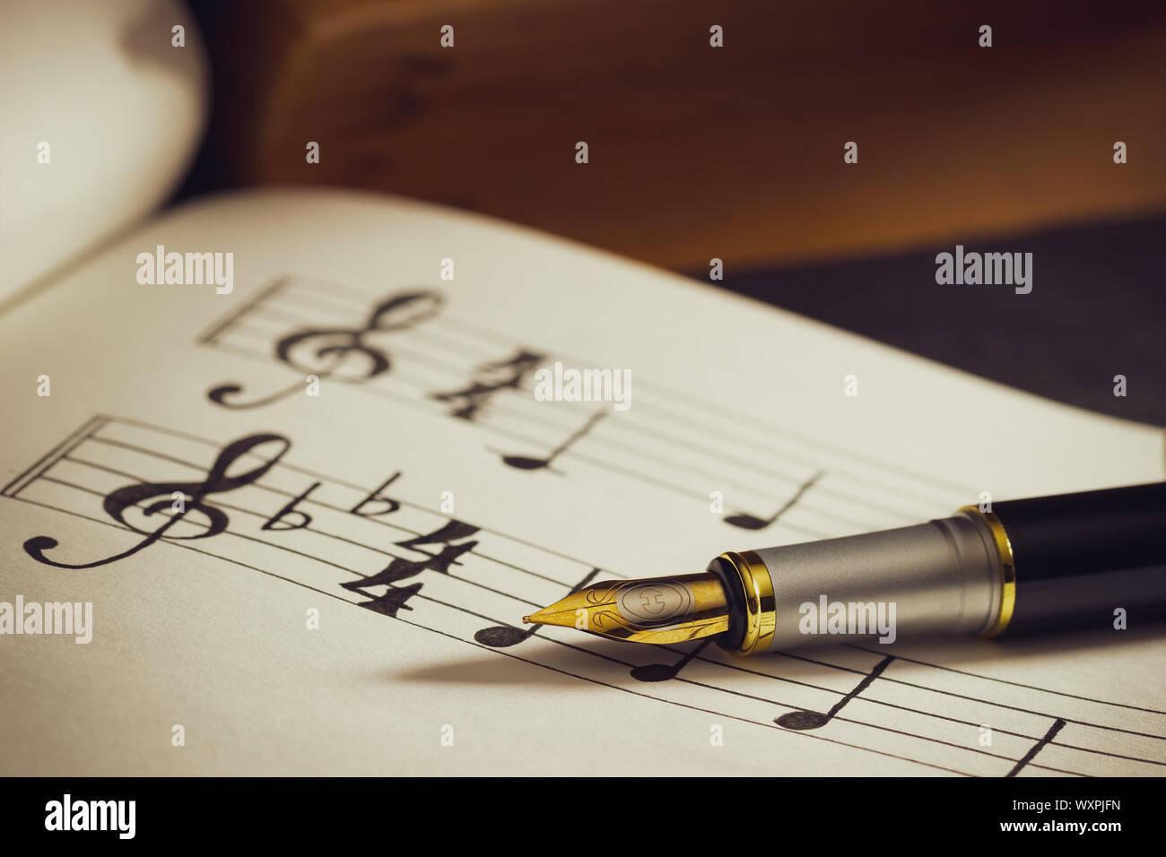 Music notes and old book on wooden table background in morning light ...