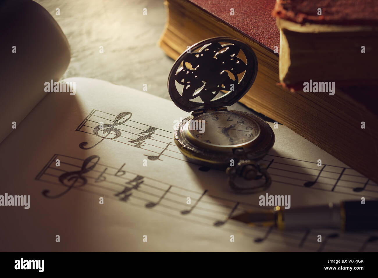 Music notes and old book with pocket watch on wooden table background ...