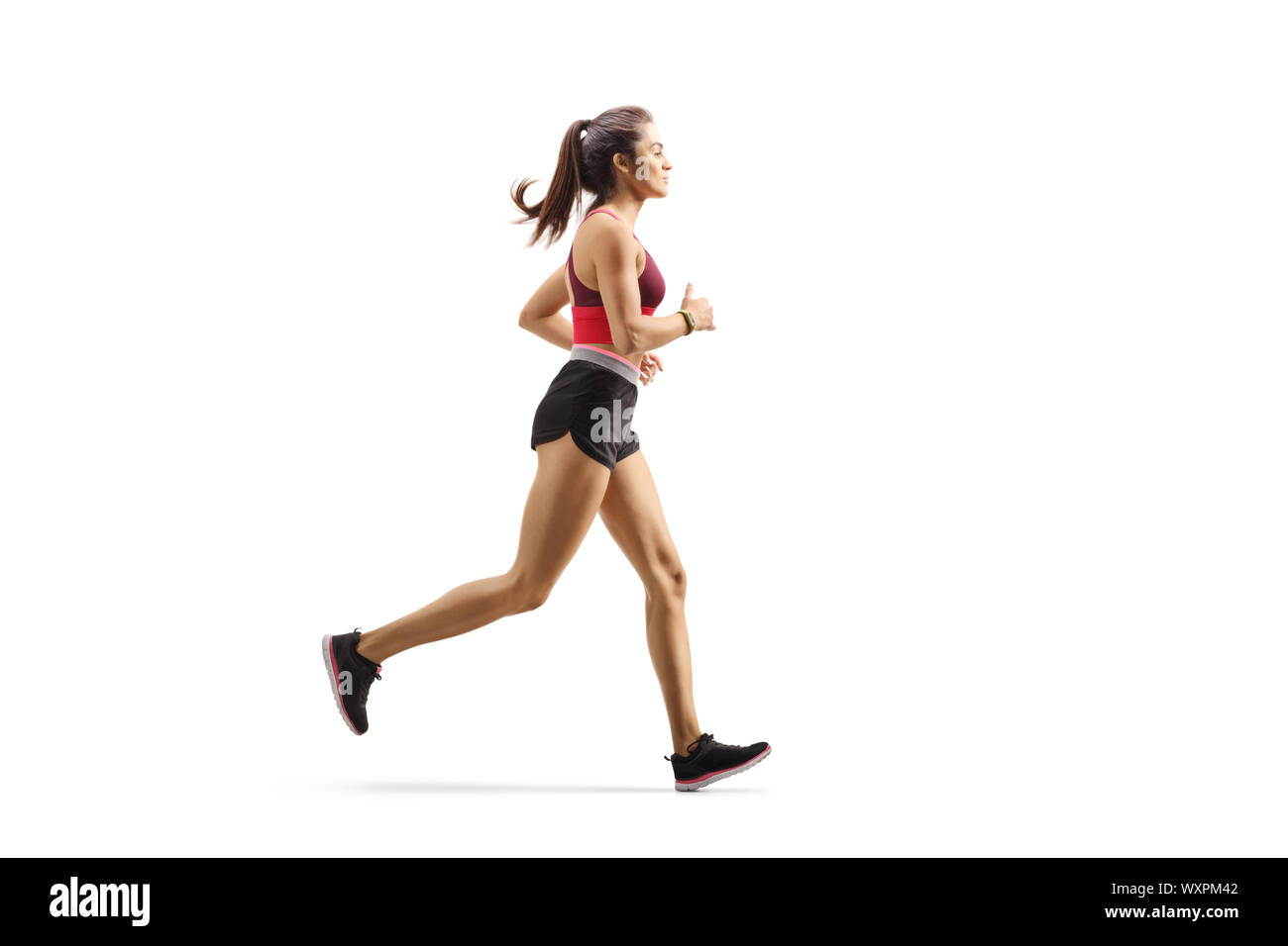 Full length profile shot of a female athlete jogging isolated on white ...