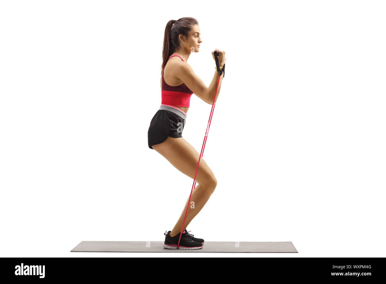 Full length profile shot of a sporty female exercising with resistance ...