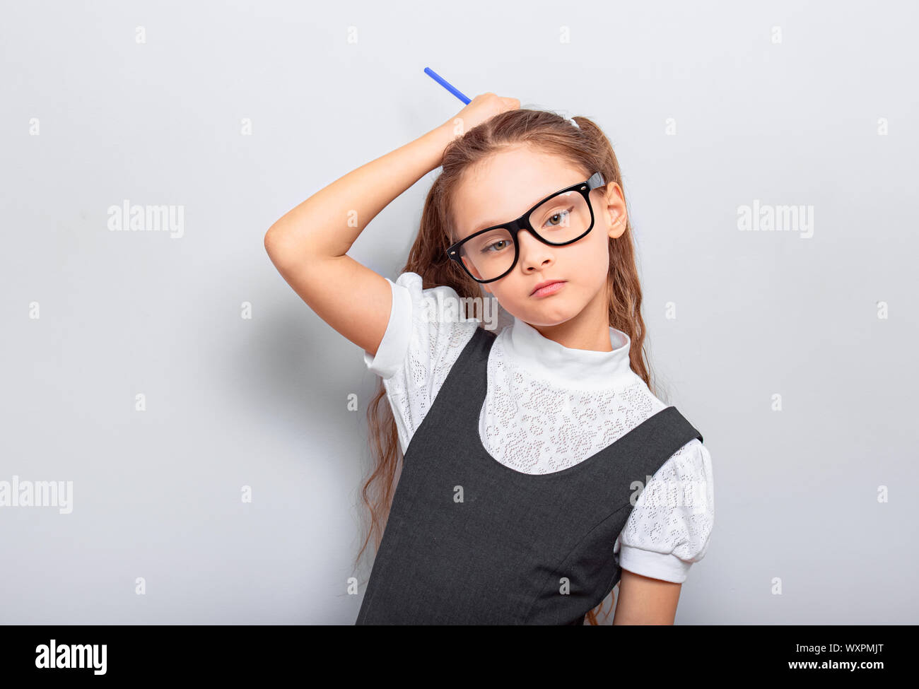 Thinking serious skeptical pupil girl in fashion eyeglasses scratching ...