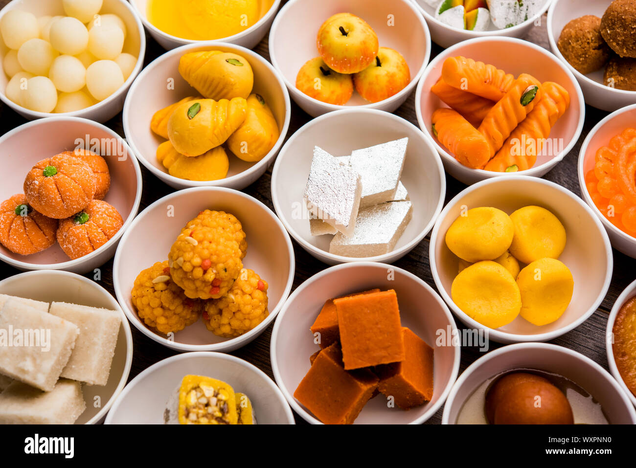 Rangoli of sweets and Farsan/snacks in bowls for Diwali with diya over ...