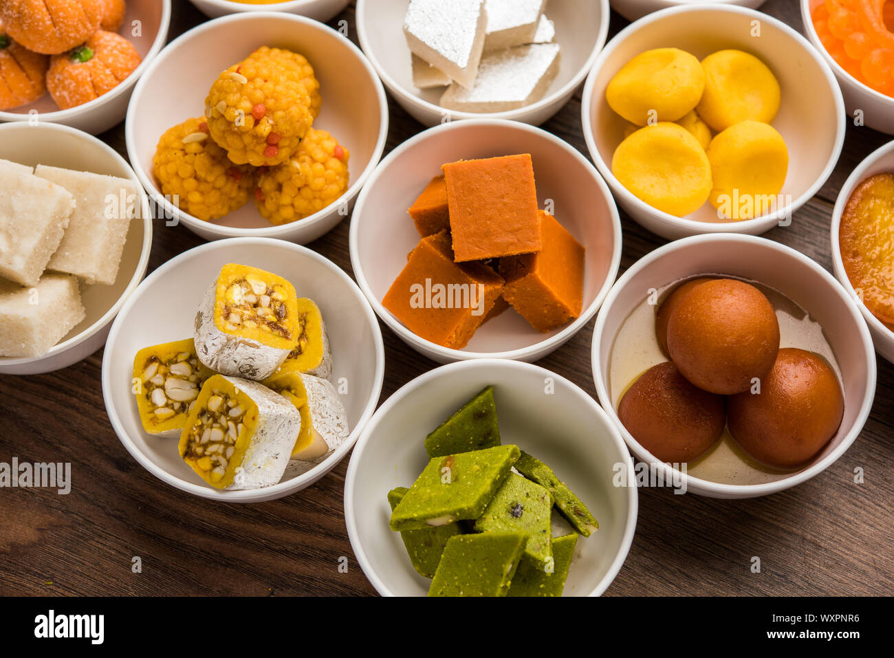 Rangoli of sweets and Farsan/snacks in bowls for Diwali with diya over ...