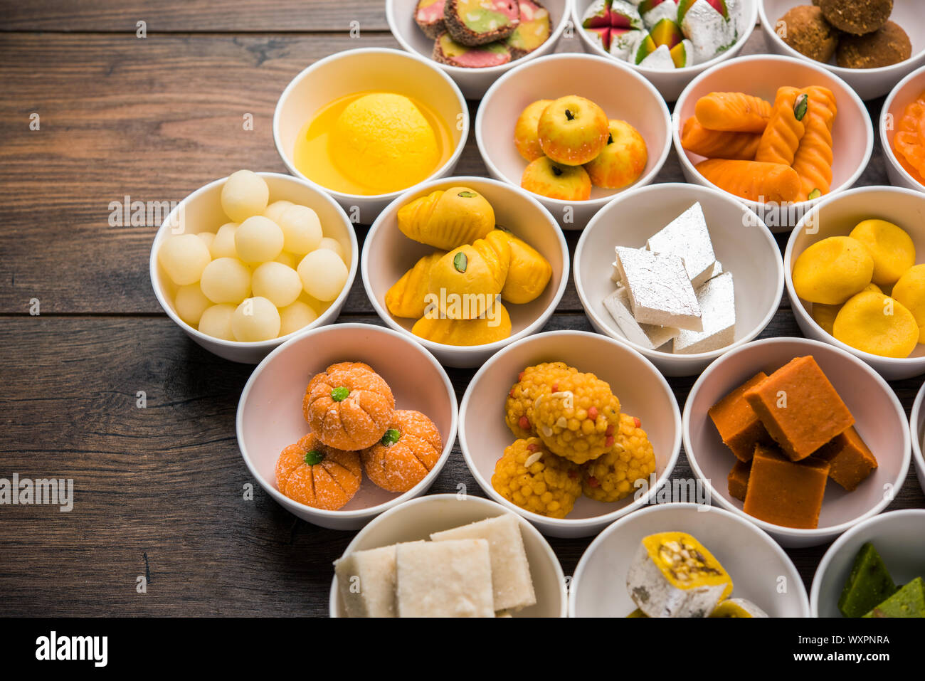 Rangoli of sweets and Farsan/snacks in bowls for Diwali with diya over ...
