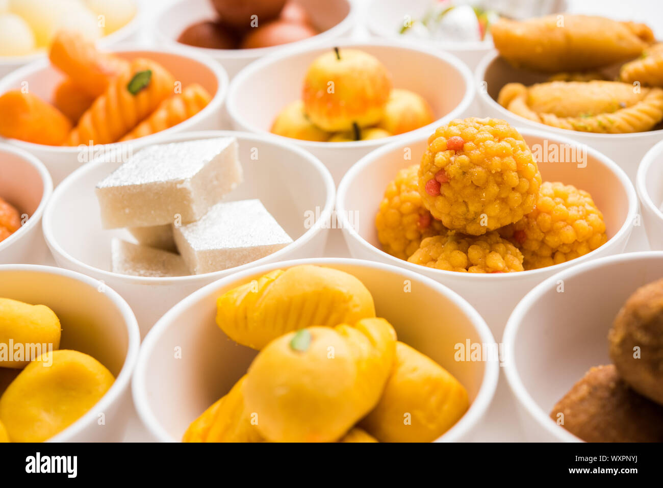 Rangoli of sweets and Farsan/snacks in bowls for Diwali with diya over ...