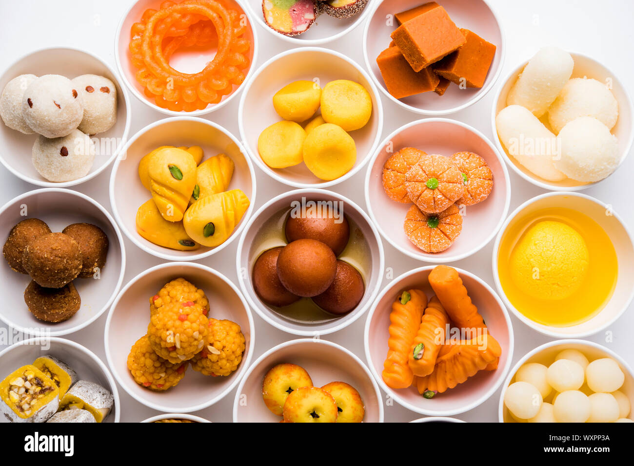 Rangoli of sweets and Farsan/snacks in bowls for Diwali with diya over ...