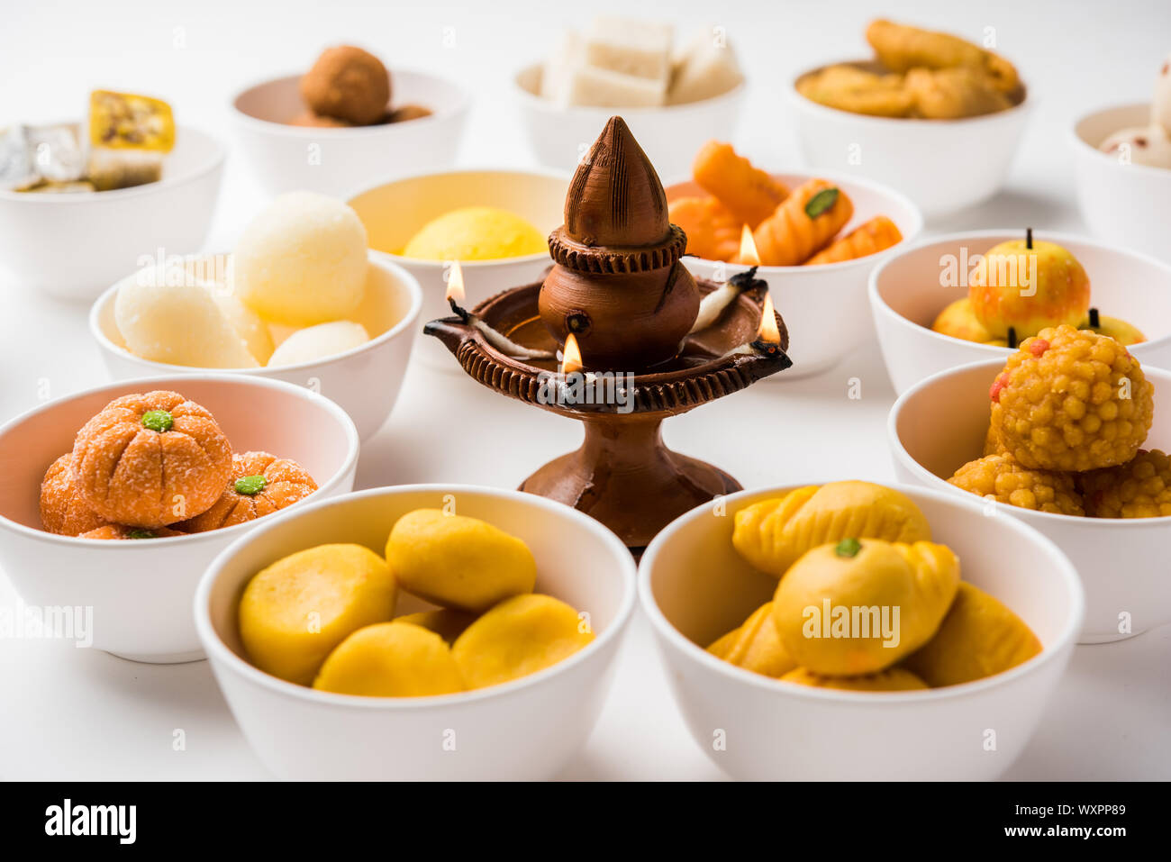 Rangoli of sweets and Farsan/snacks in bowls for Diwali with diya over ...