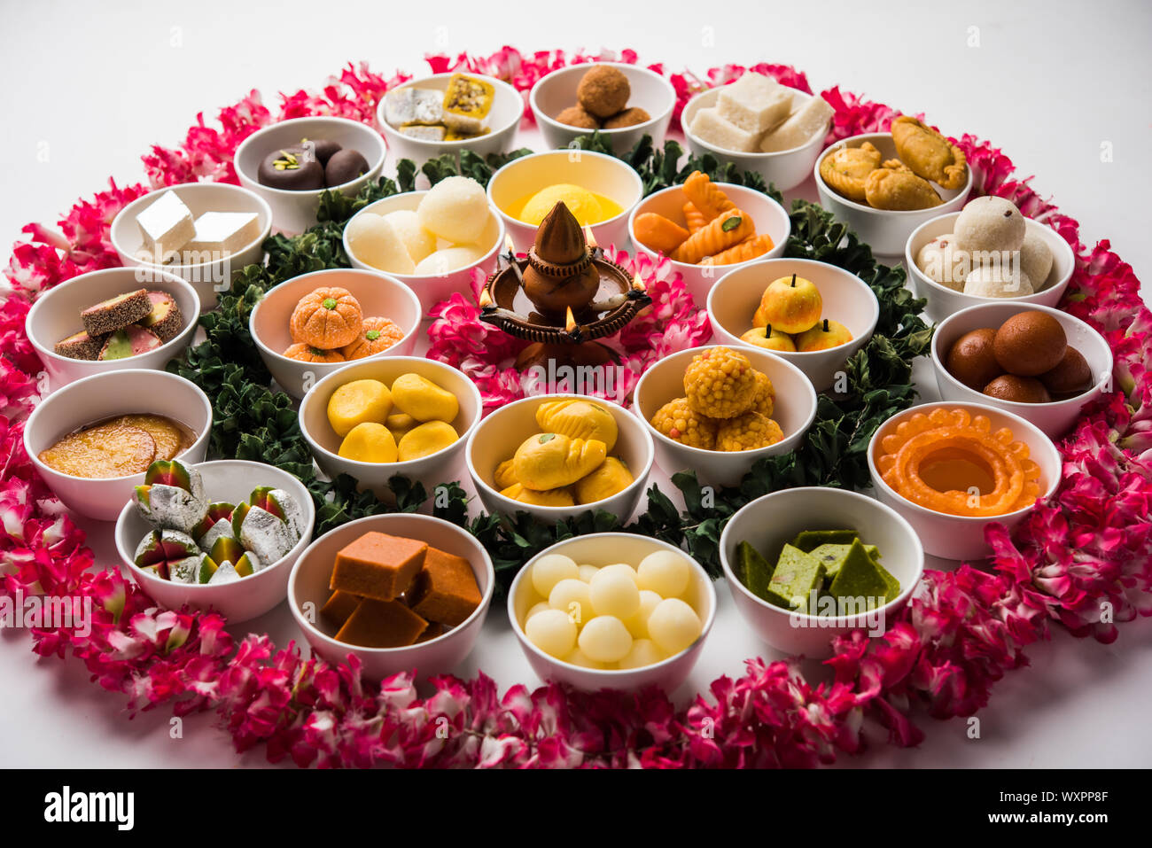 Rangoli of sweets and Farsan/snacks in bowls for Diwali with diya over ...