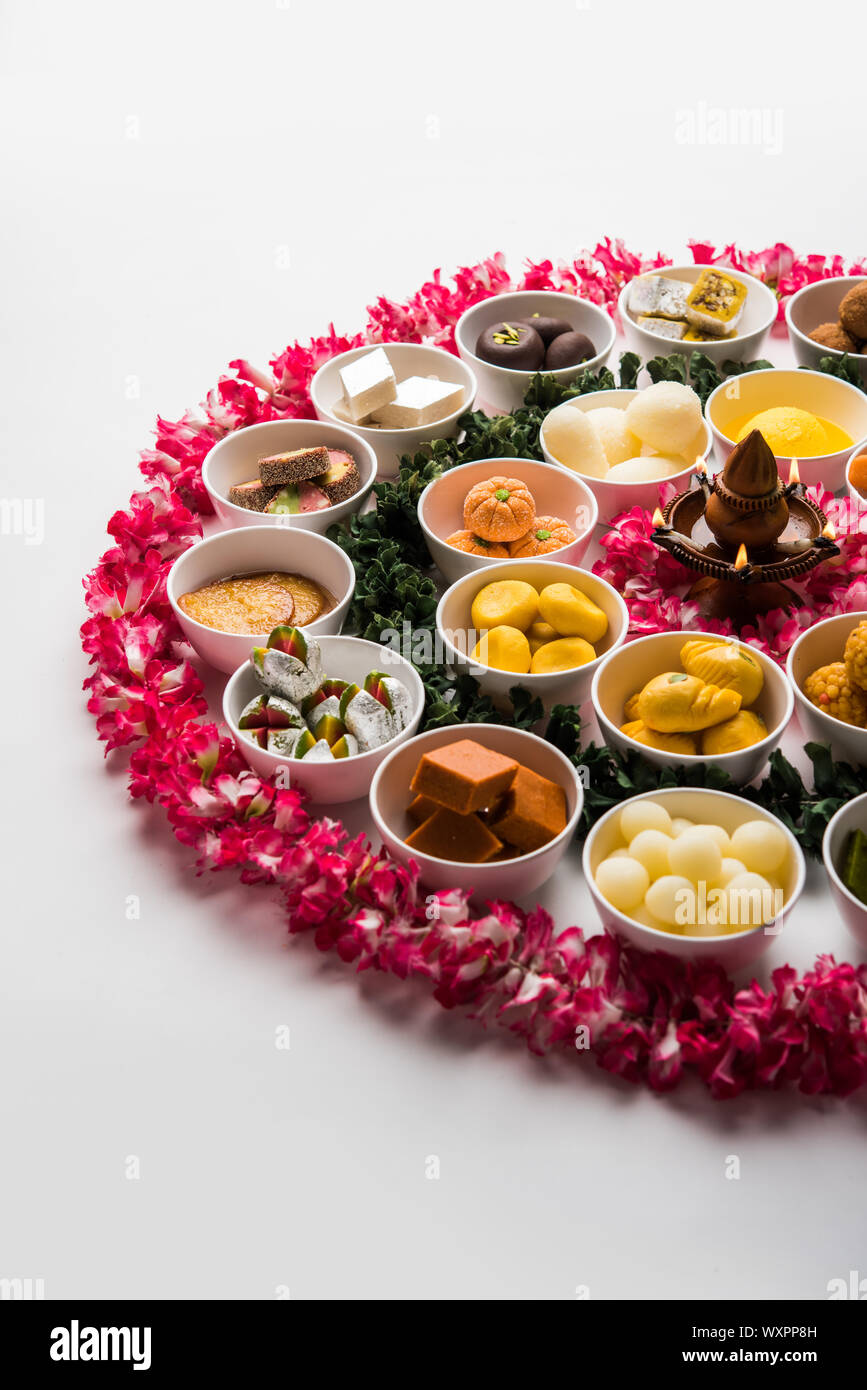 Rangoli of sweets and Farsan/snacks in bowls for Diwali with diya over ...