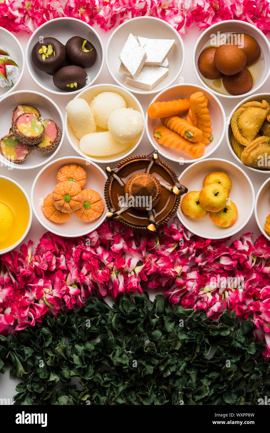 Rangoli of sweets and Farsan/snacks in bowls for Diwali with diya over ...