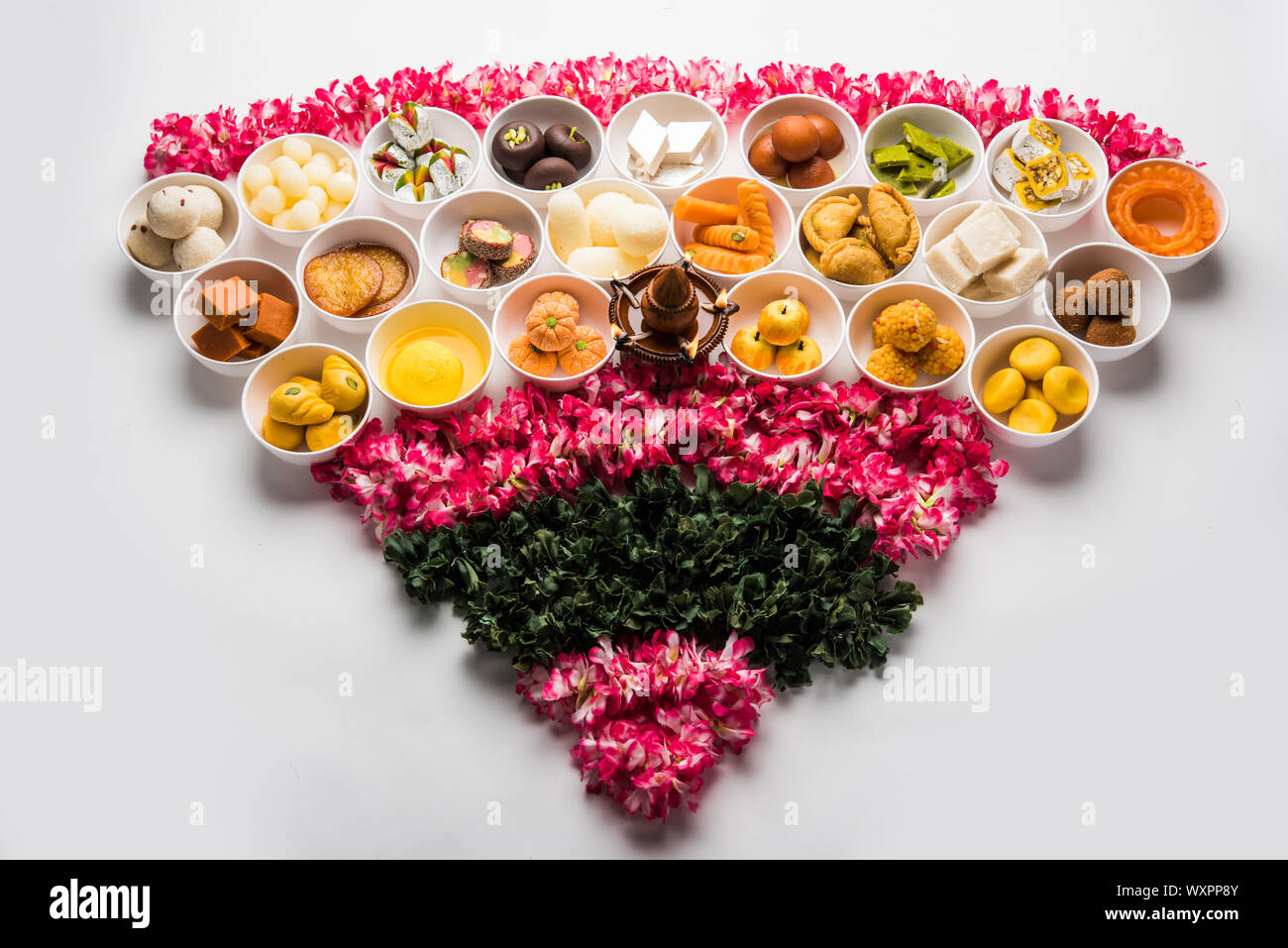 Rangoli of sweets and Farsan/snacks in bowls for Diwali with diya over ...