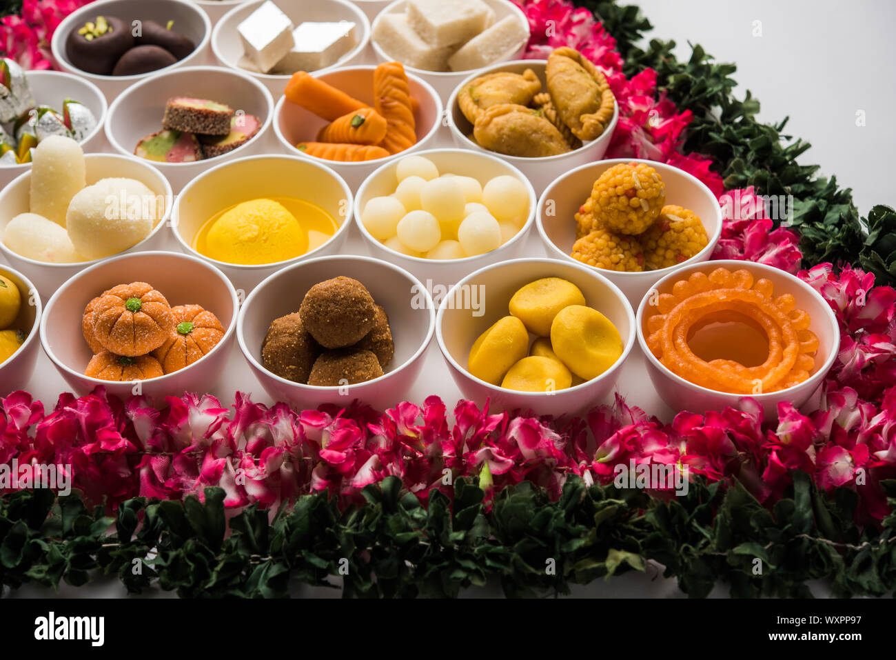 Rangoli of sweets and Farsan/snacks in bowls for Diwali with diya over ...