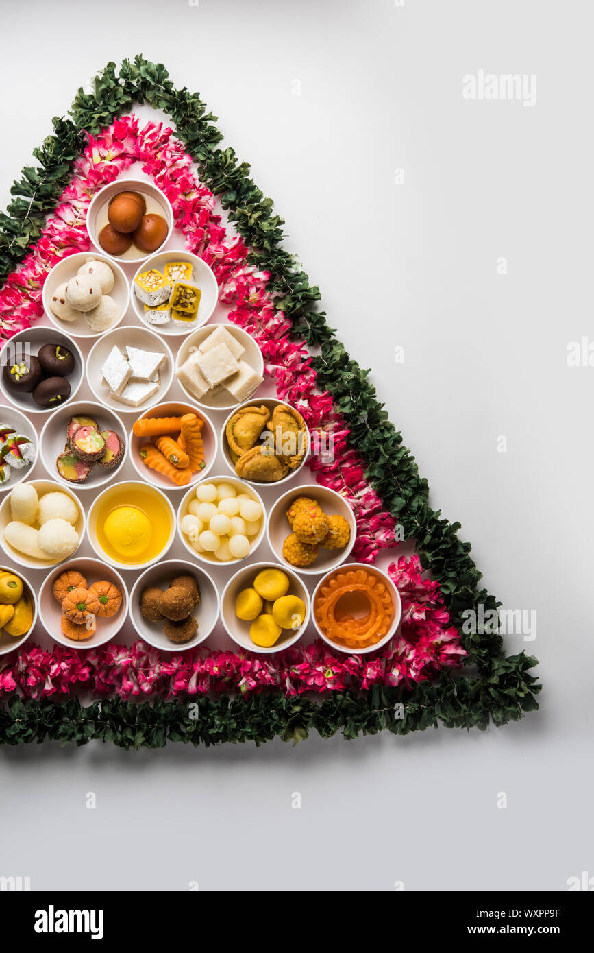 Rangoli of sweets and Farsan/snacks in bowls for Diwali with diya over ...