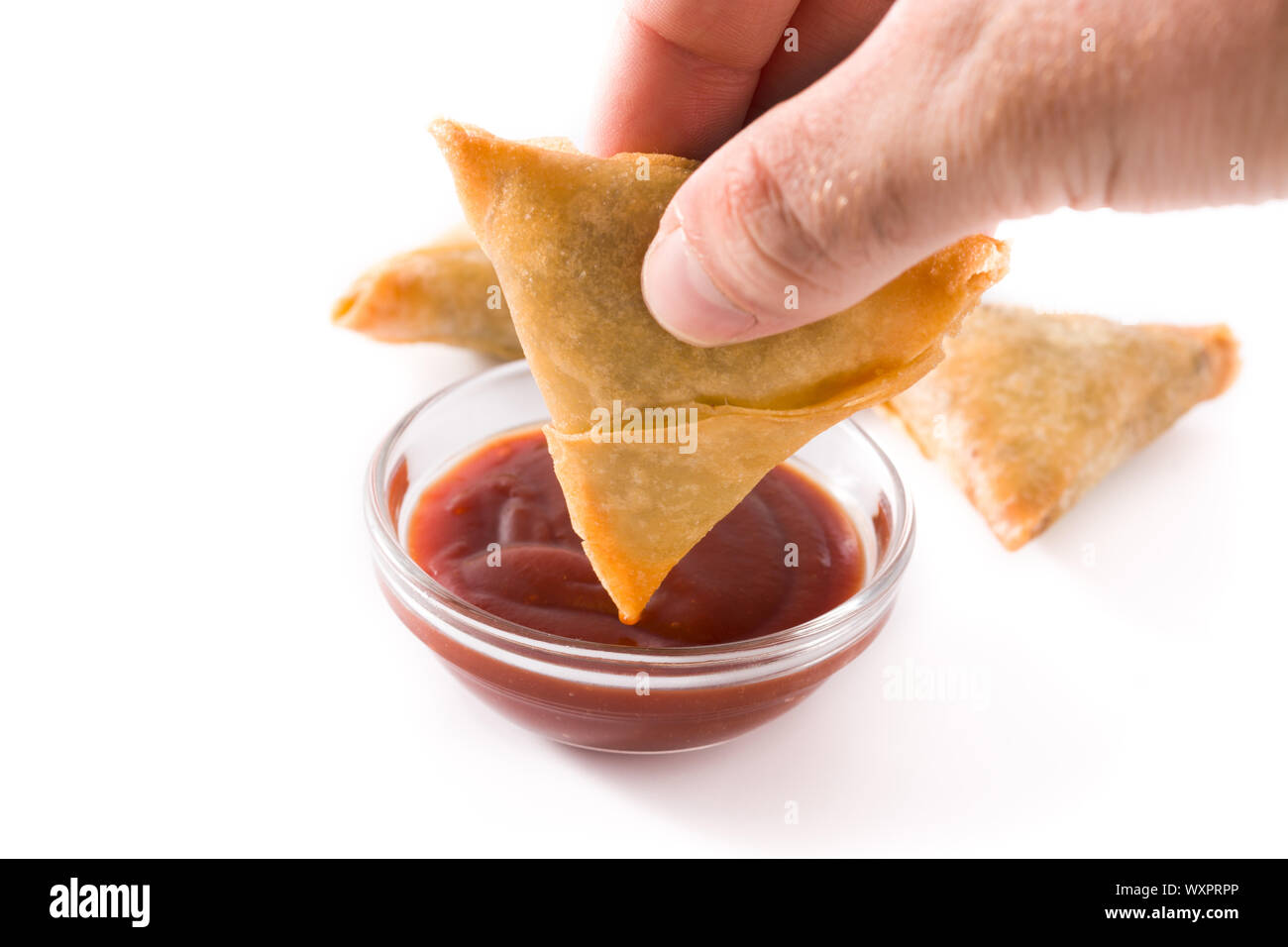 Hand with samosa dipping in sweet and sour sauce isolated on white ...