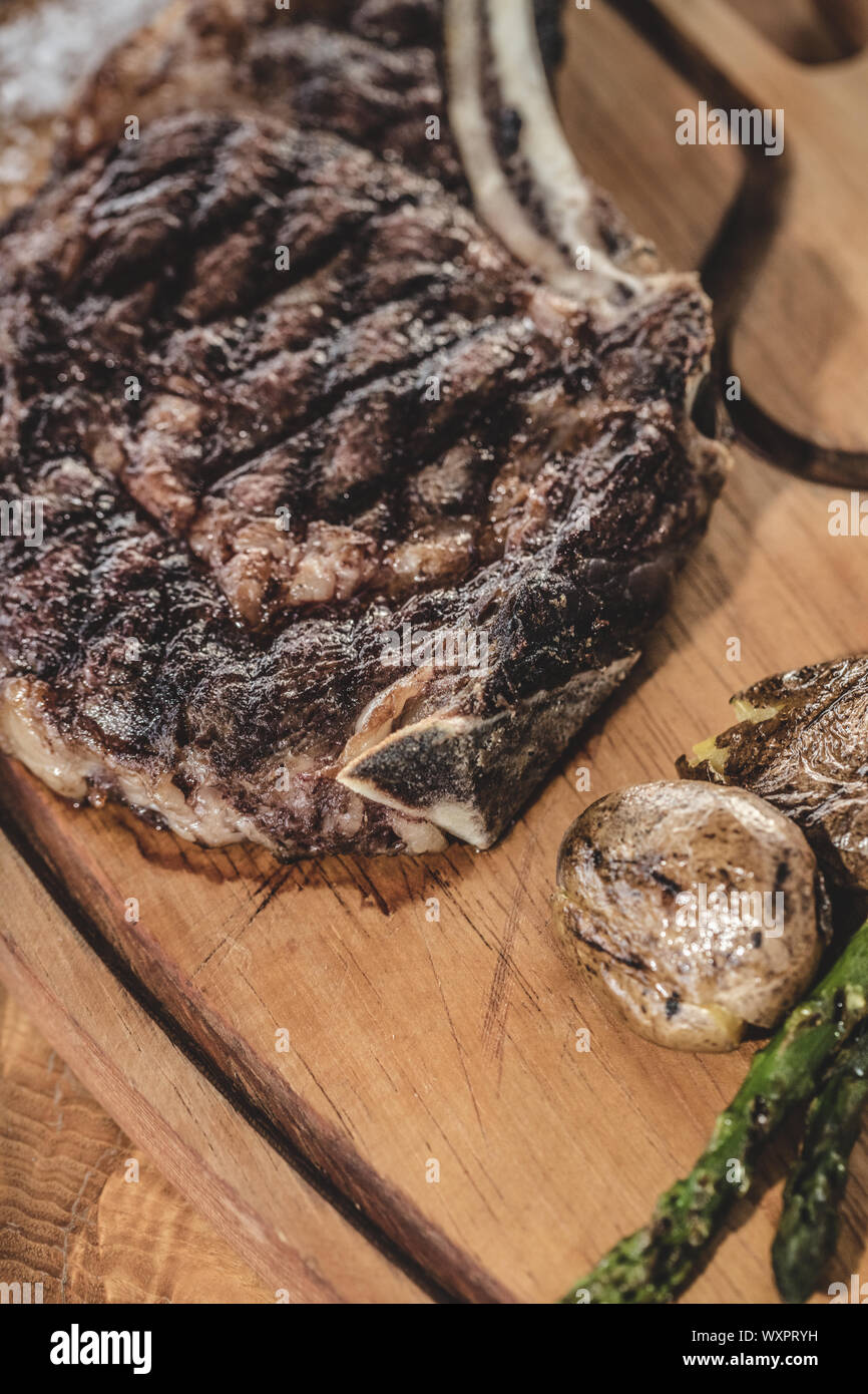 Grilled beef chop served on wooden serving plate with grilled ...