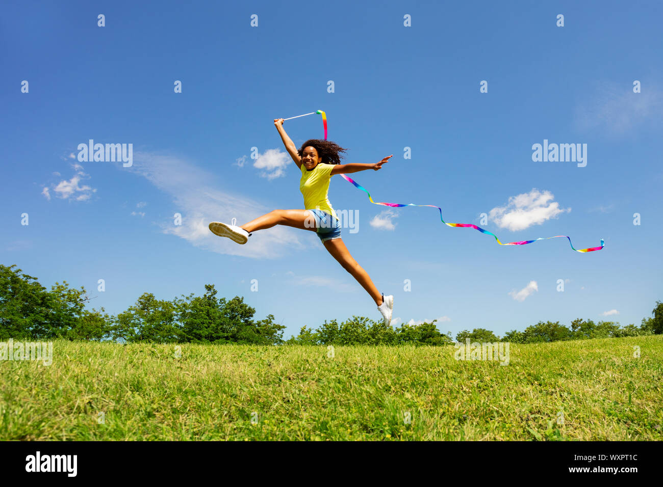 Cute girl long jump waving colorful ribbon Stock Photo - Alamy