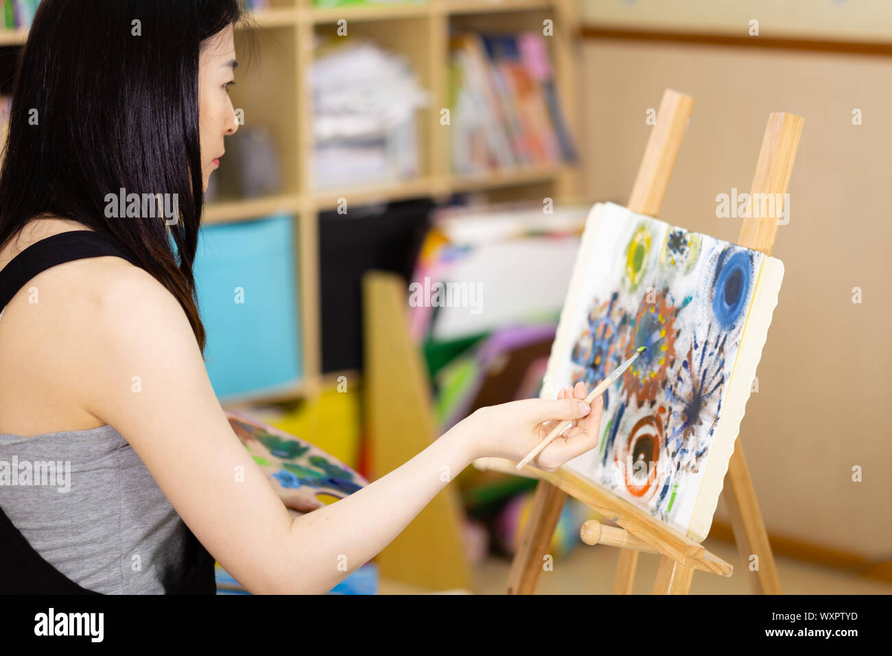 Artist painting oil painting on an easel Stock Photo - Alamy
