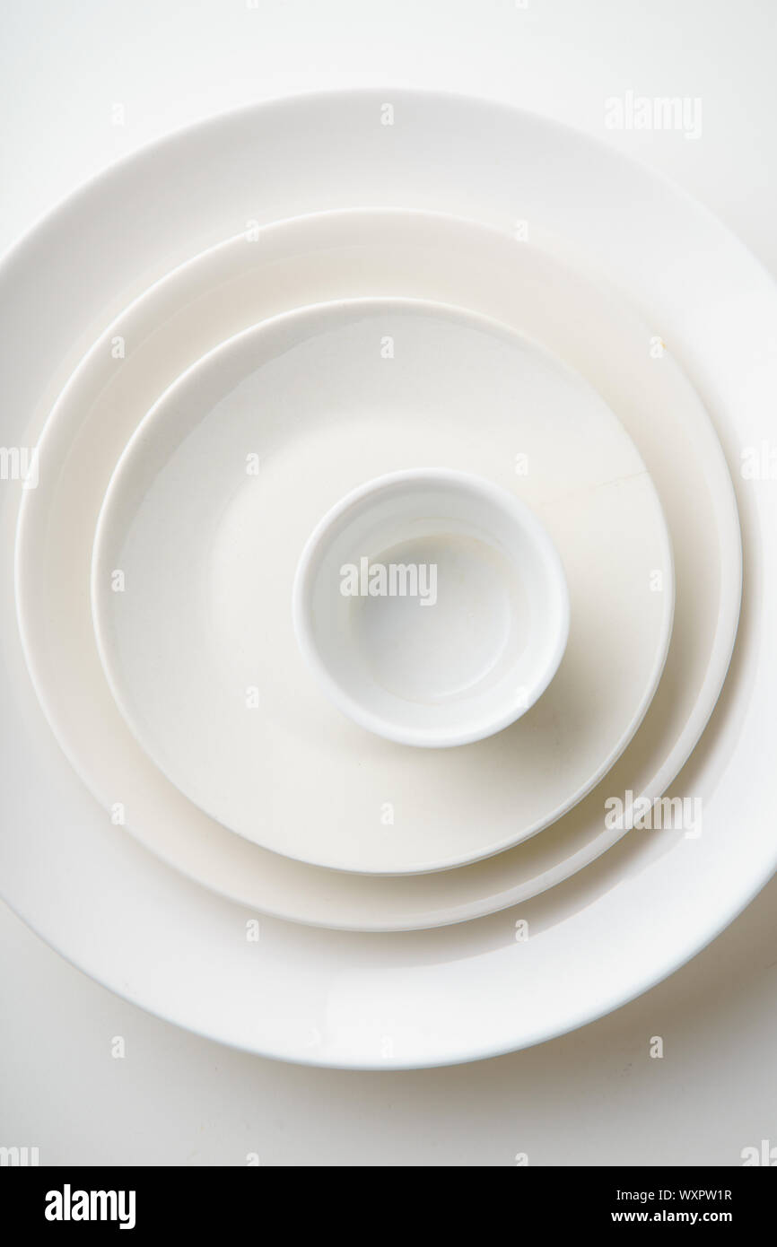 Porcelain plates of various form and size on white background. Overhead ...