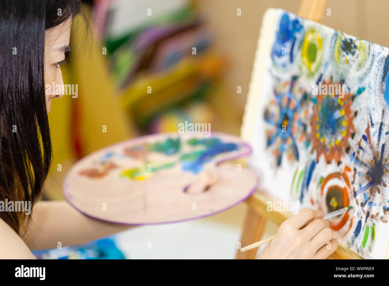 Artist painting oil painting on an easel Stock Photo - Alamy