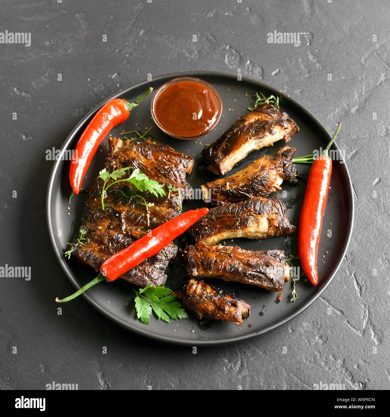 Spicy grilled spare ribs on plate over black stone background. Tasty ...