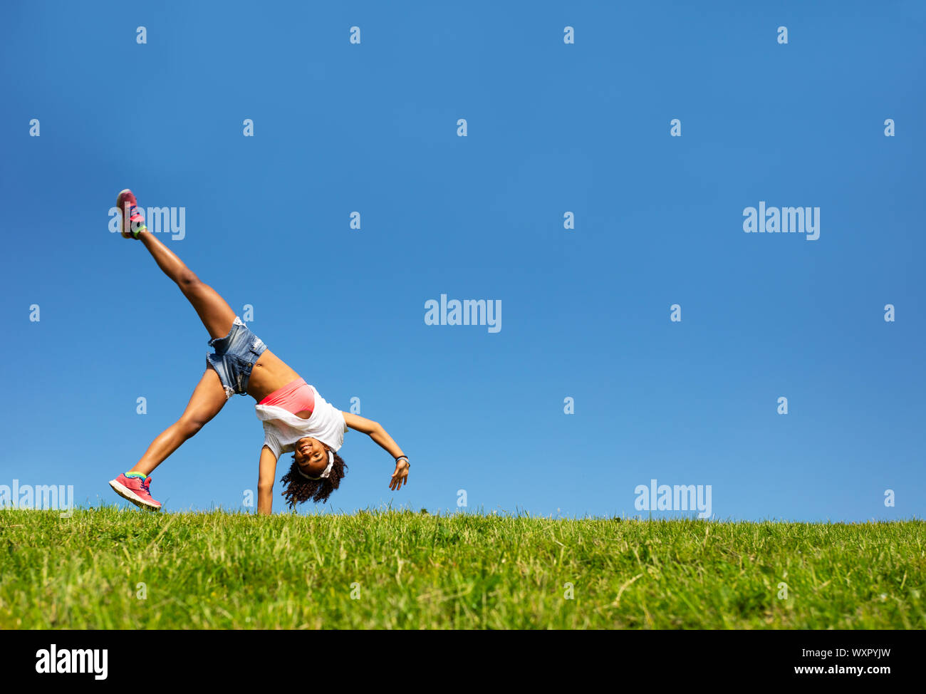 Happy girl walk on hands over blue sky and grass Stock Photo - Alamy