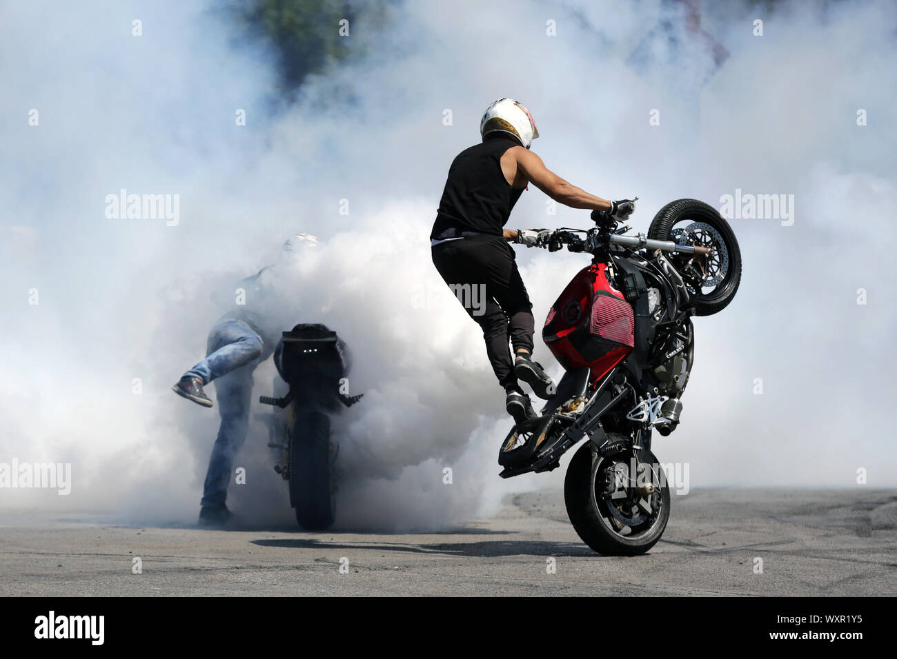 Two motorbikes burn wheels on a race track. White smoke Stock Photo - Alamy